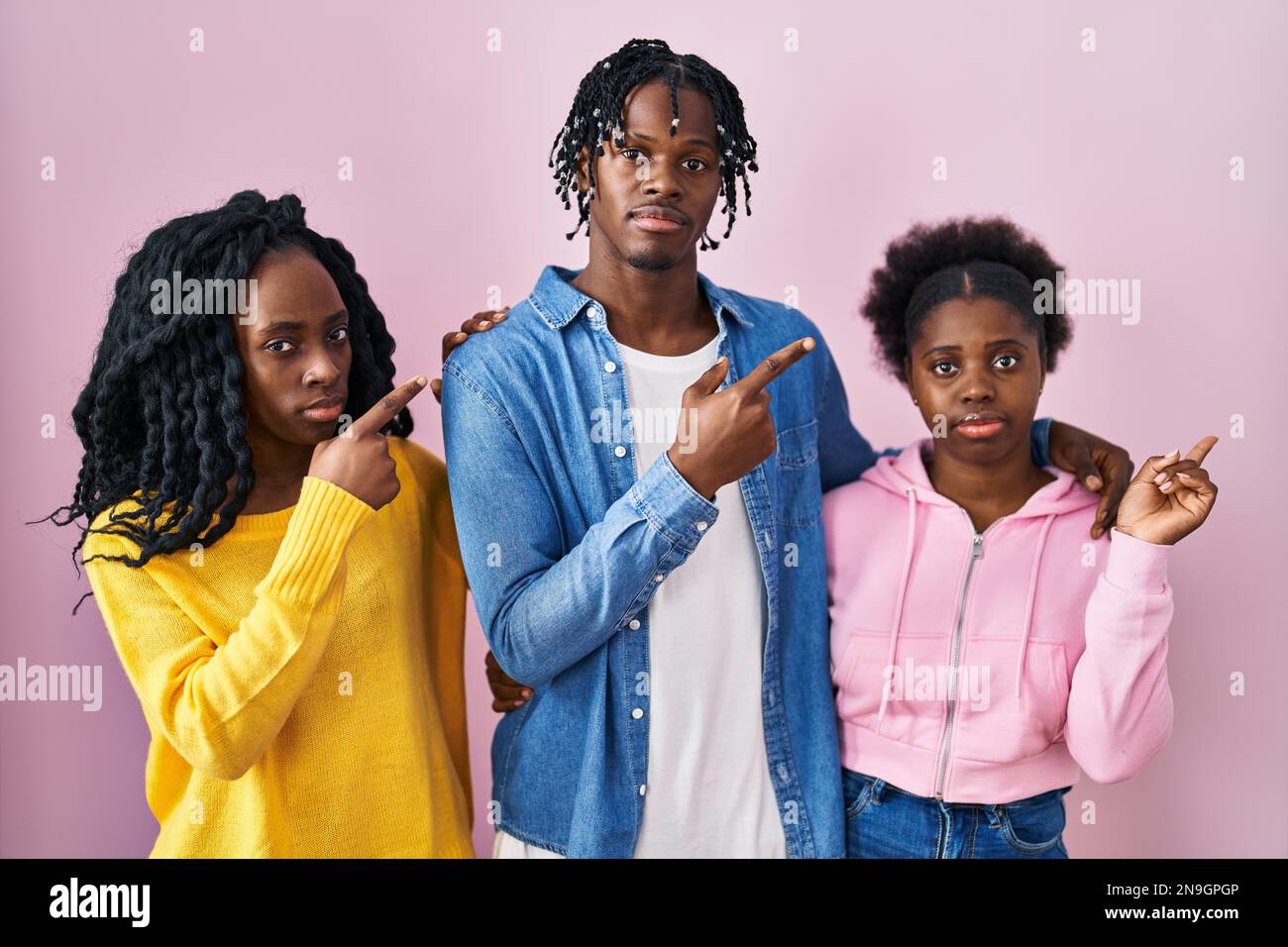 Group of three young black people standing together over pink ...