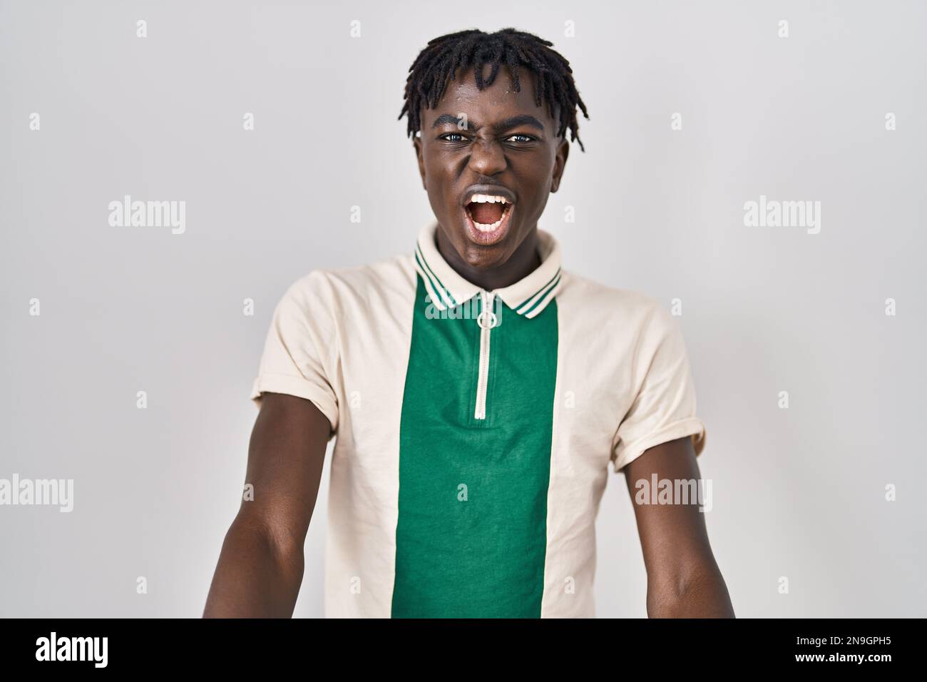 African man with dreadlocks standing over isolated background angry and ...