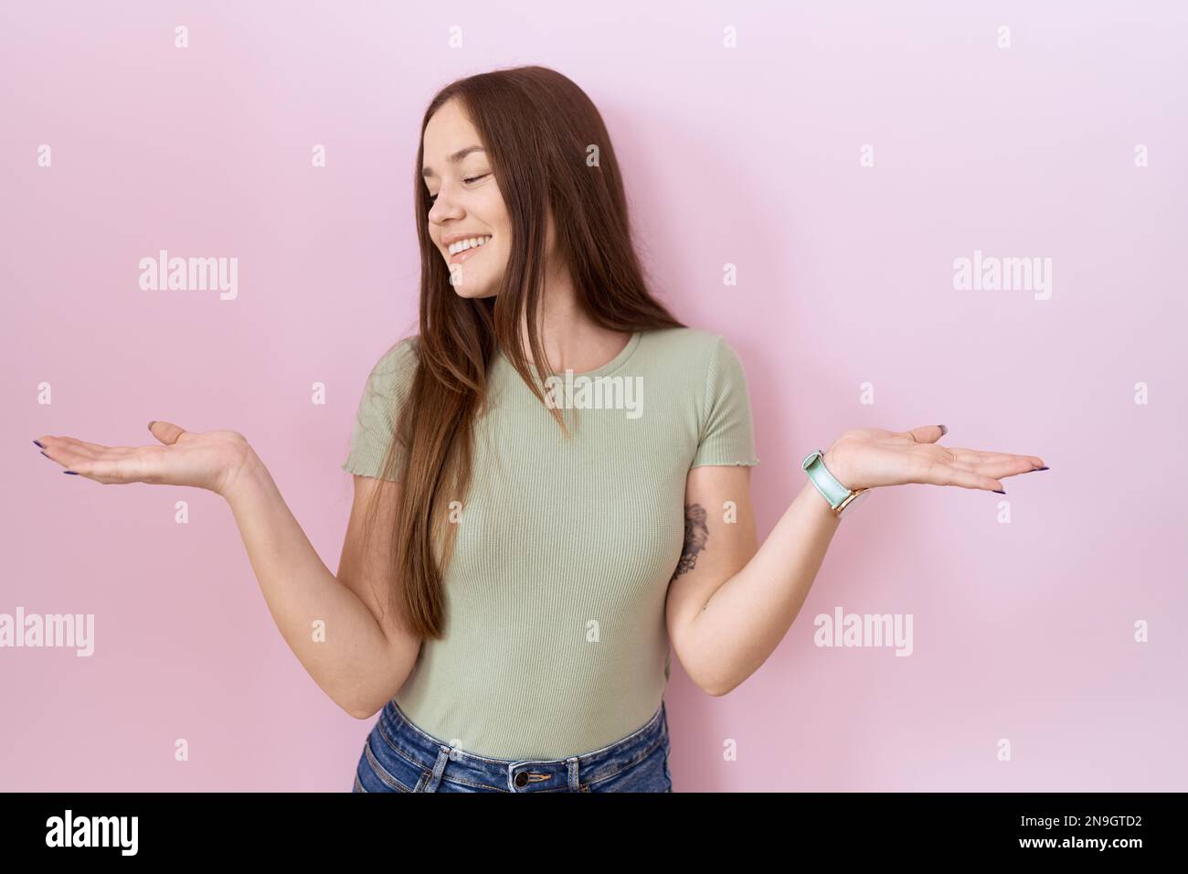 Beautiful brunette woman standing over pink background smiling showing ...