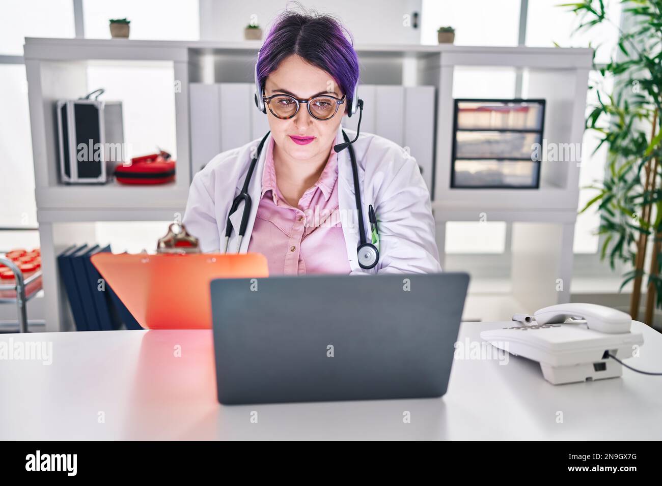 Young beautiful plus size woman doctor writing on document having ...