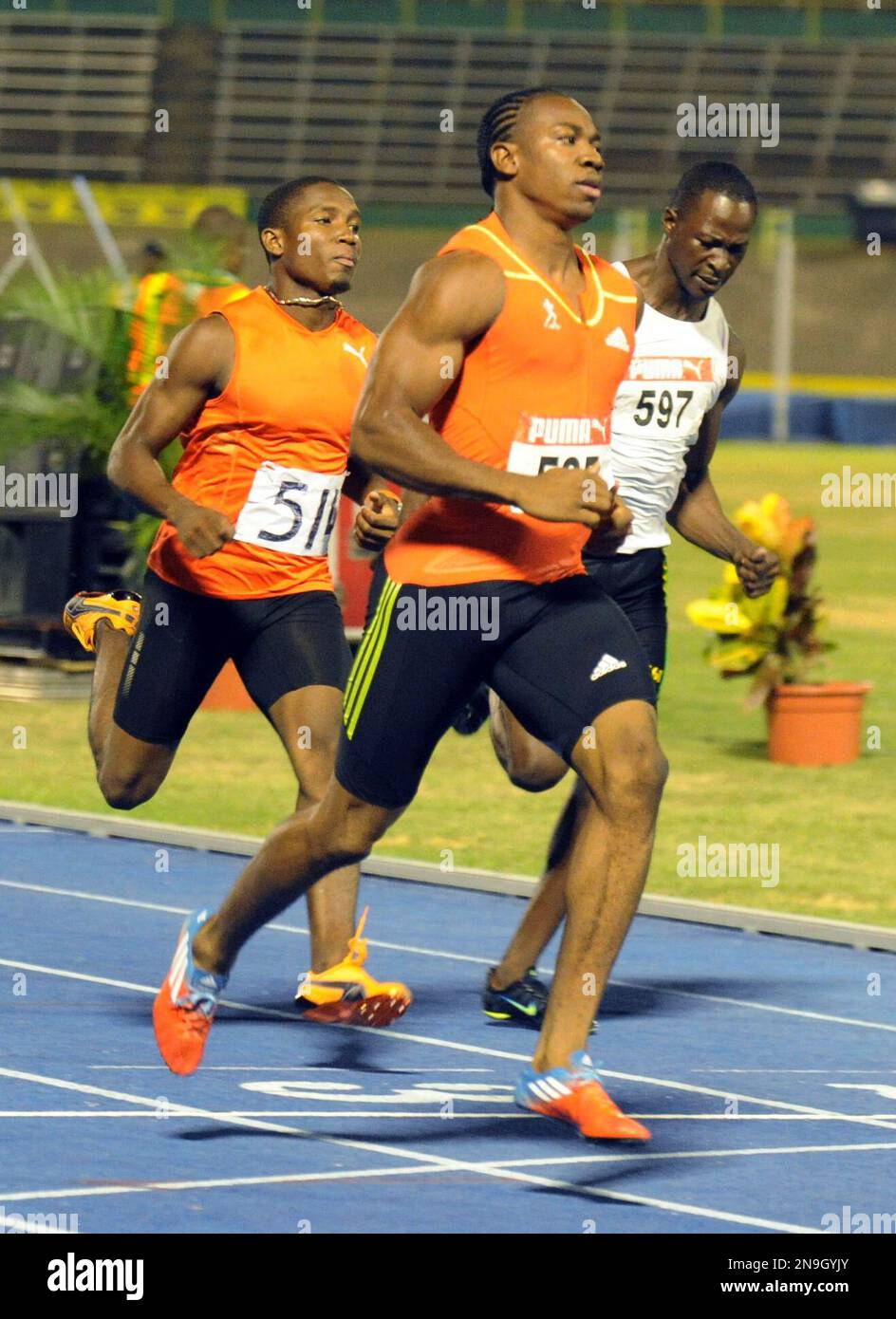 World champion Yohan Blake, center, crosses the finish line ahead ...