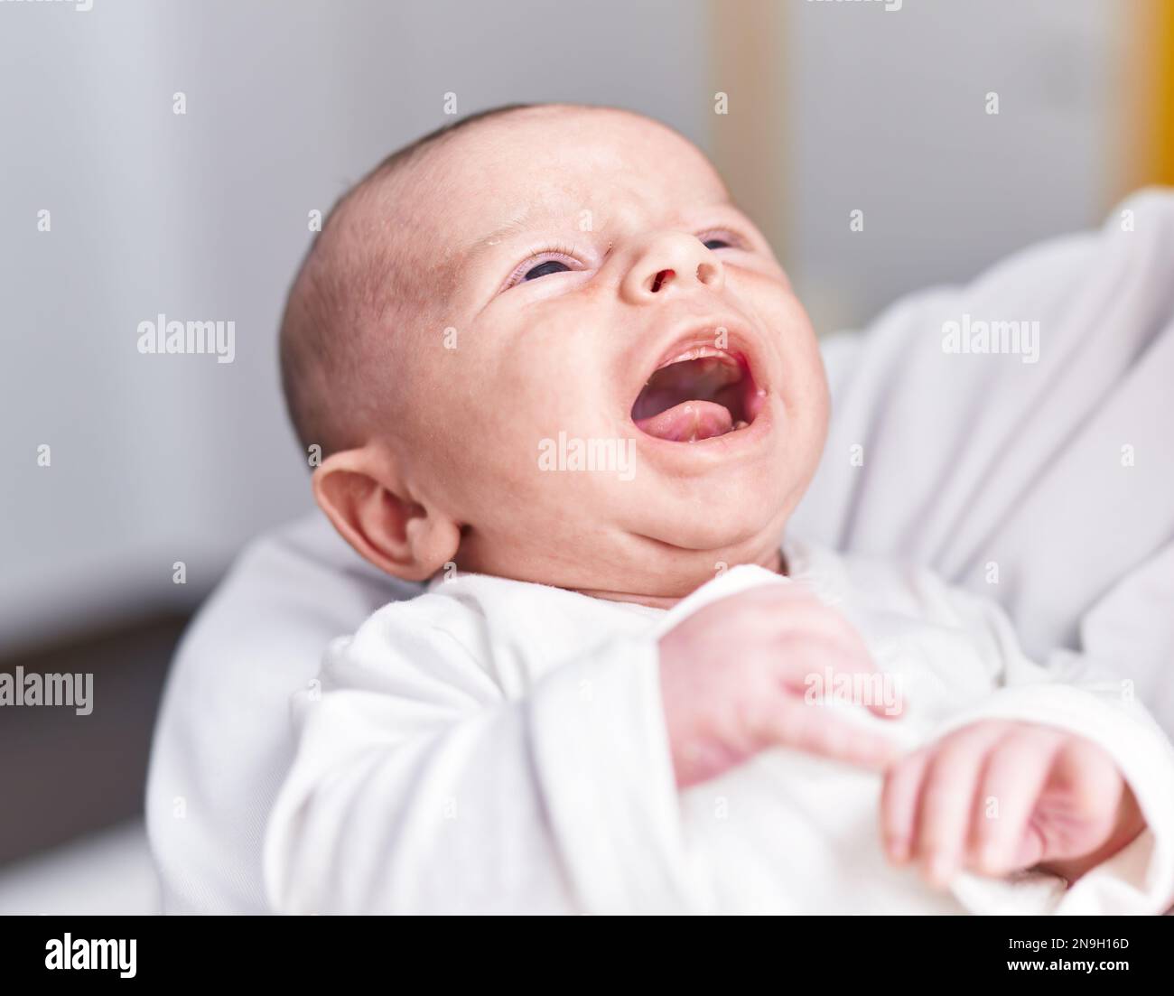 Adorable caucasian baby crying on mother arms at home Stock Photo - Alamy