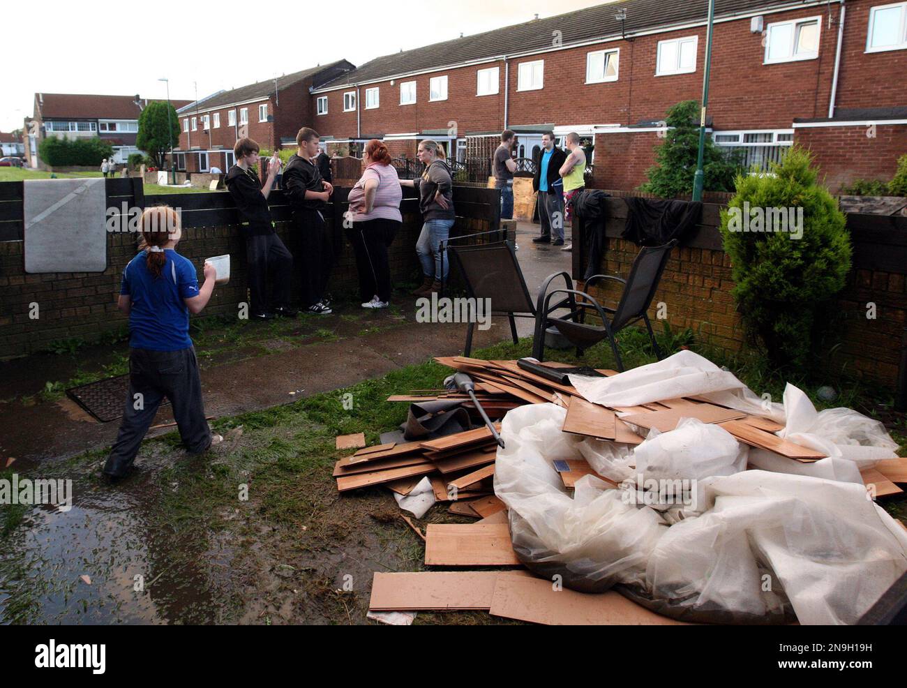 People stand outside their flooded homes after torrential downpours ...