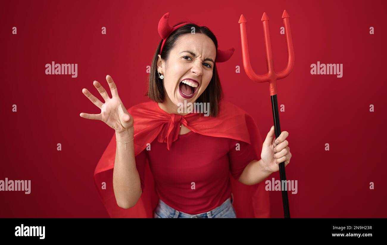 Young beautiful hispanic woman wearing devil costume doing scare ...