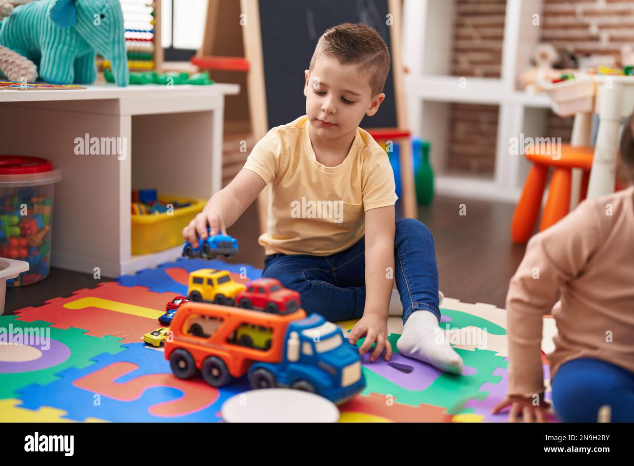 Two kids playing with cars toy sitting on floor at kindergarten Stock ...