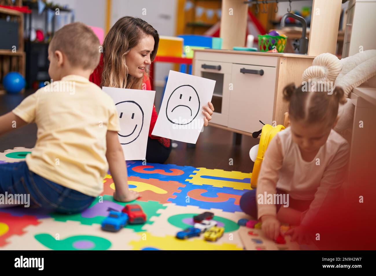 Teacher with boy and girl sitting on table having emotion therapy at ...