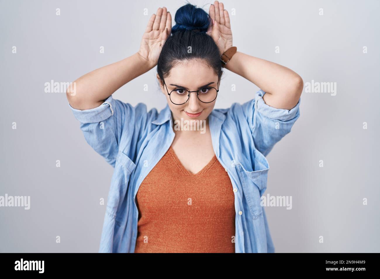 Young modern girl with blue hair standing over white background doing ...