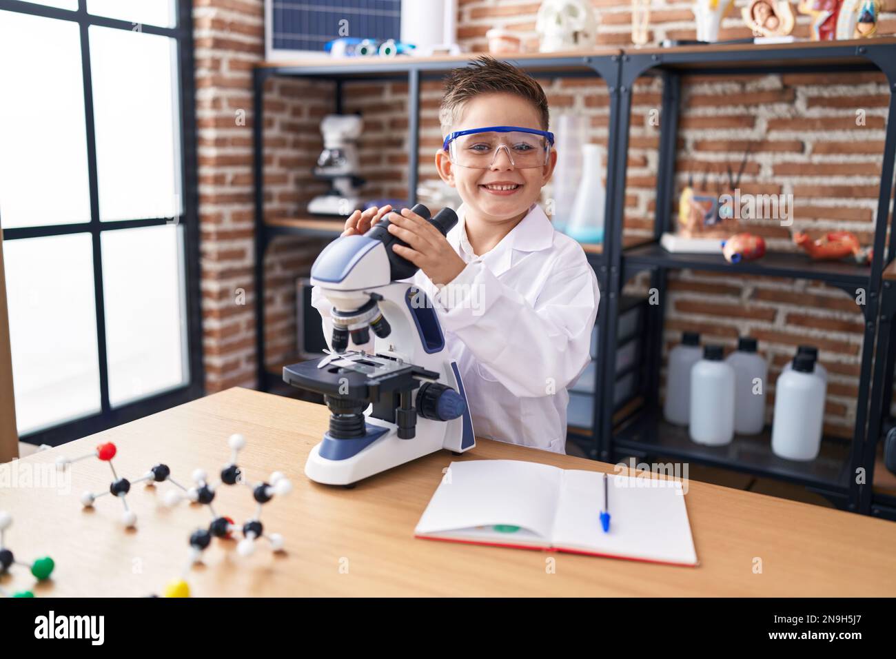 Adorable hispanic boy student smiling confident using microscope at ...