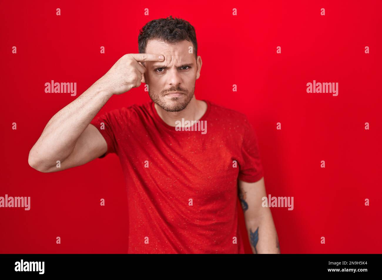 Young hispanic man standing over red background pointing unhappy to ...