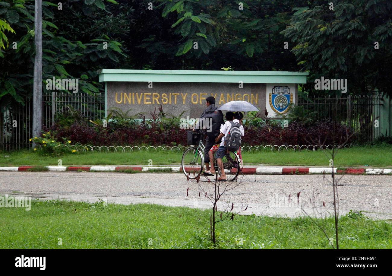 People ride a bicycle on a road leading to the entrance gate of Yangon ...