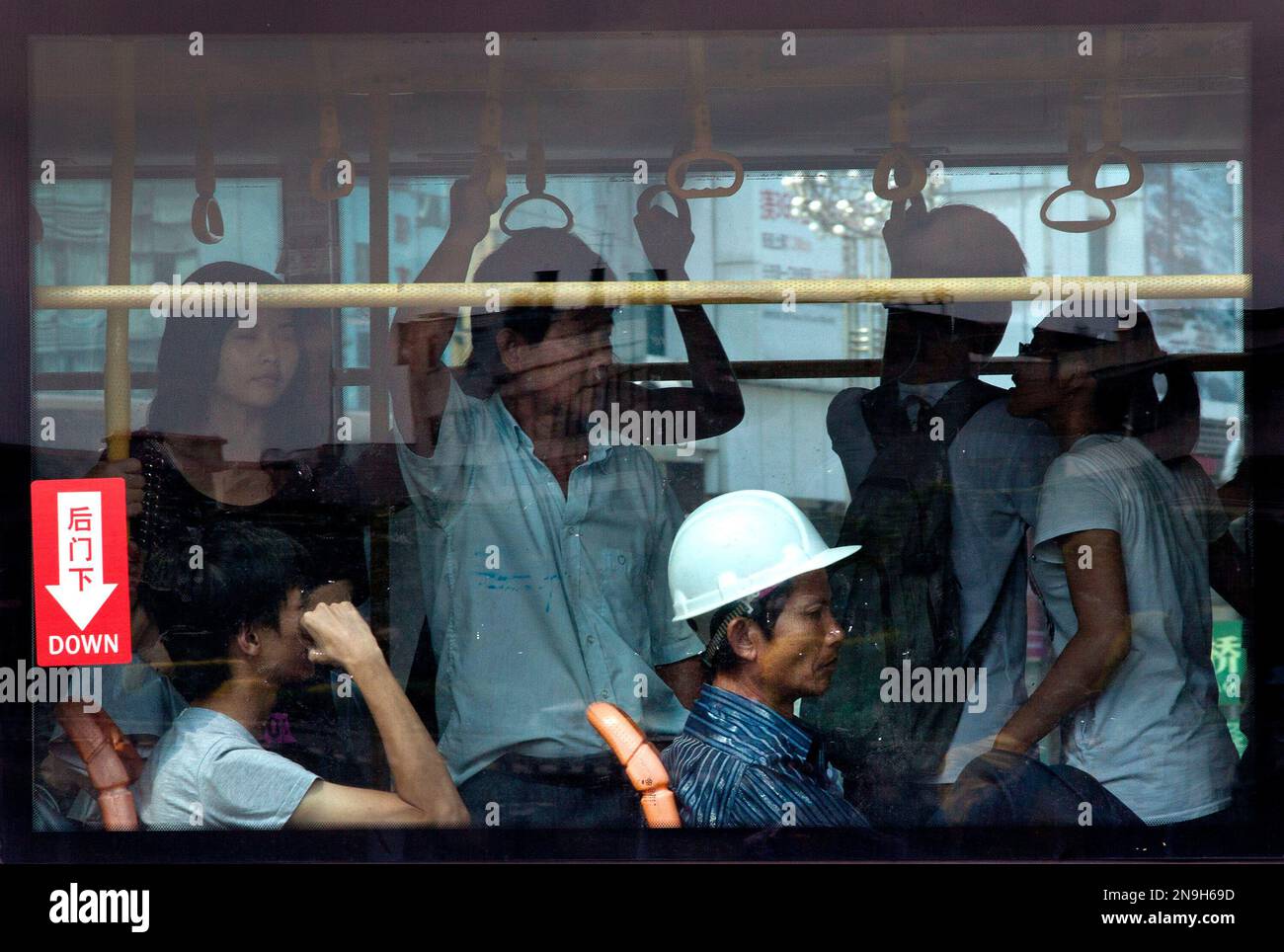 A commuter wears a construction helmet while sitting inside a crowded ...