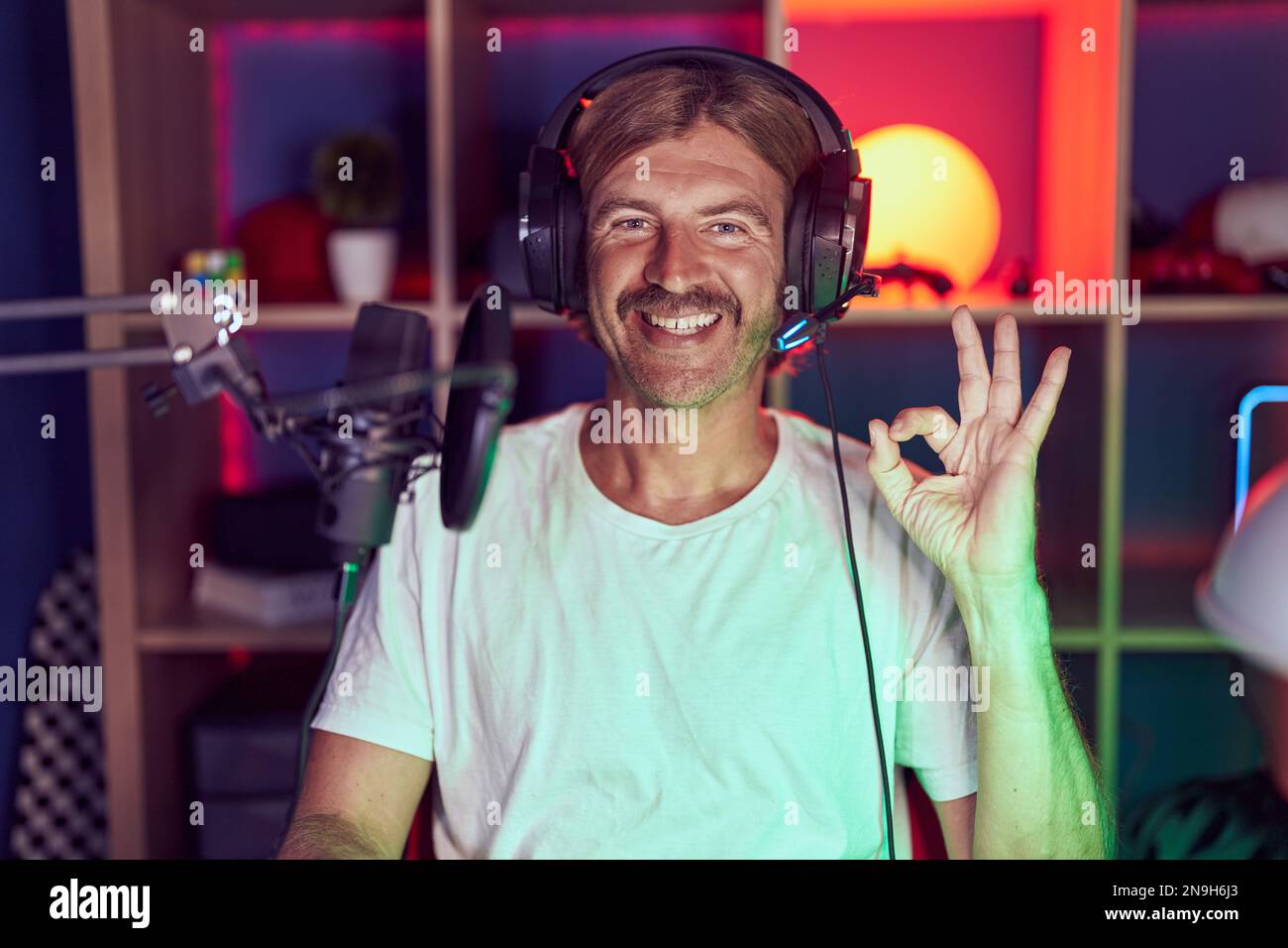 Caucasian man with mustache playing video games wearing headphones ...