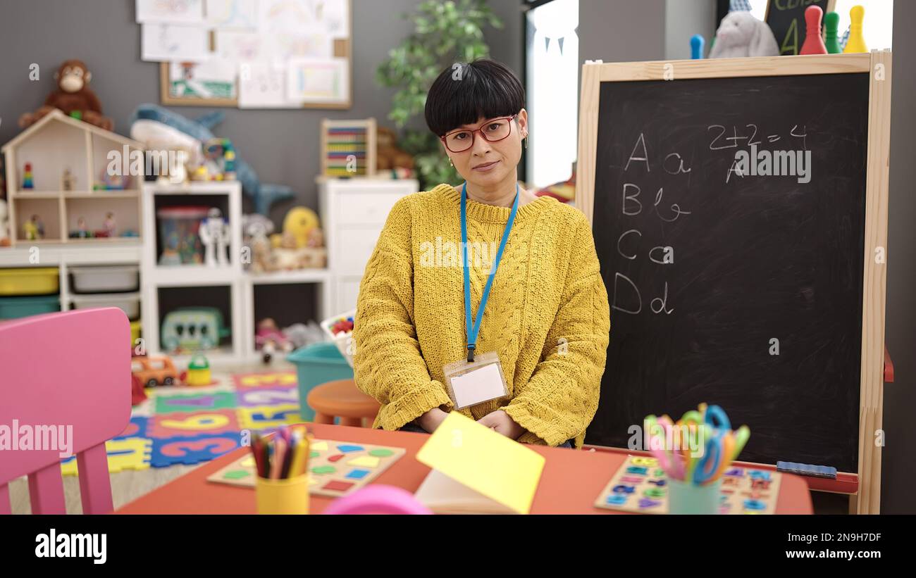 Young chinese woman preschool teacher sitting on chair with relaxed ...