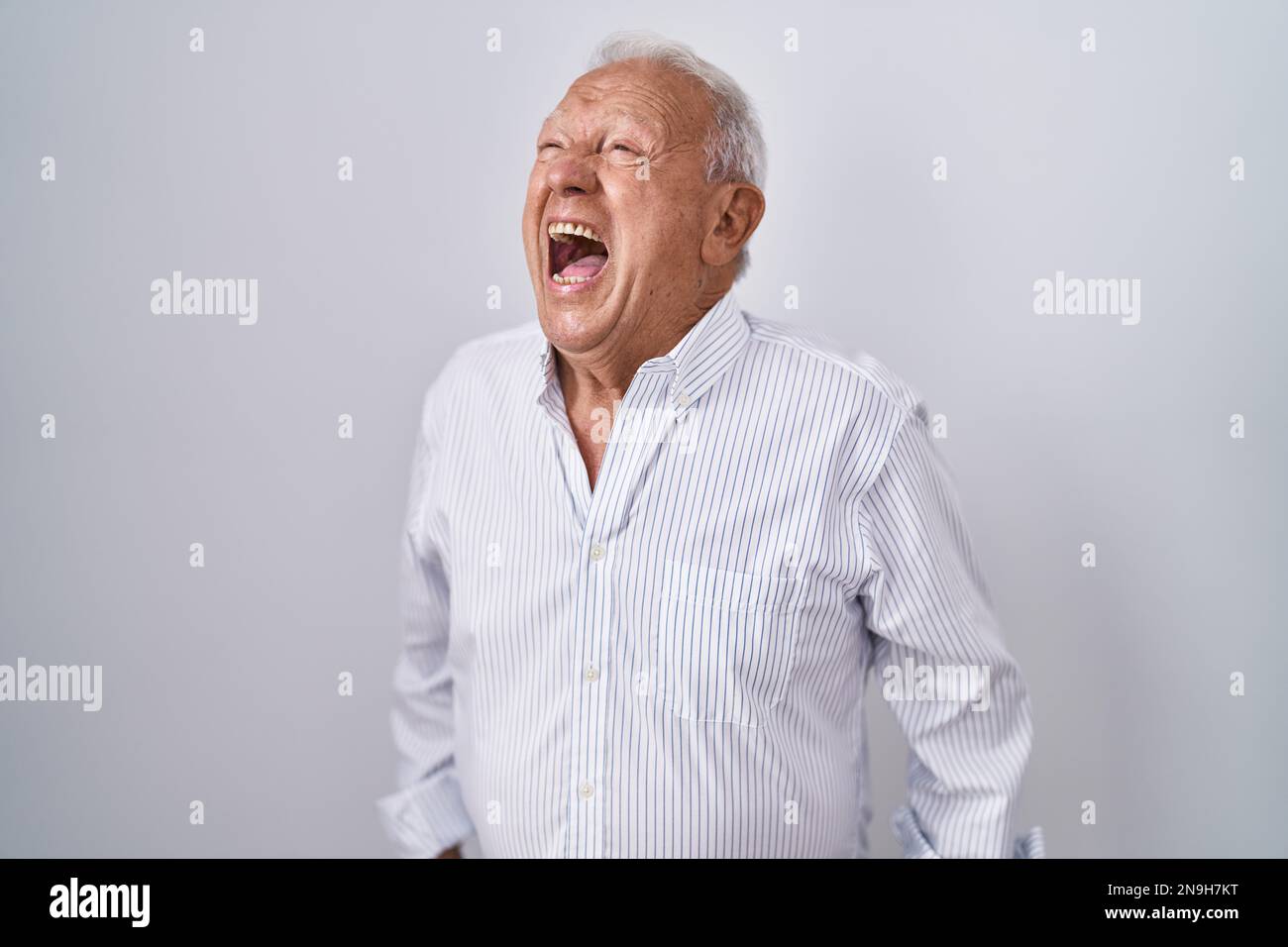 Senior man with grey hair standing over isolated background angry and ...