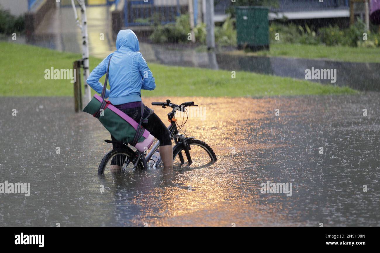 A cyclist tries to make her way through a flooded road in heavy ...