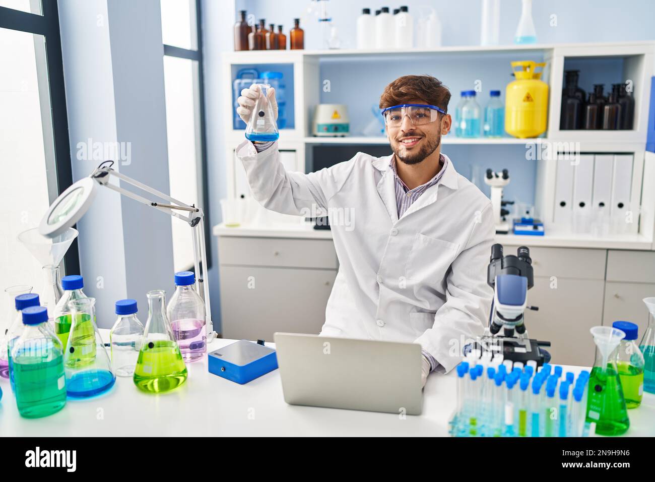 Young arab man scientist using laptop measuring liquid at laboratory Stock Photo - Alamy