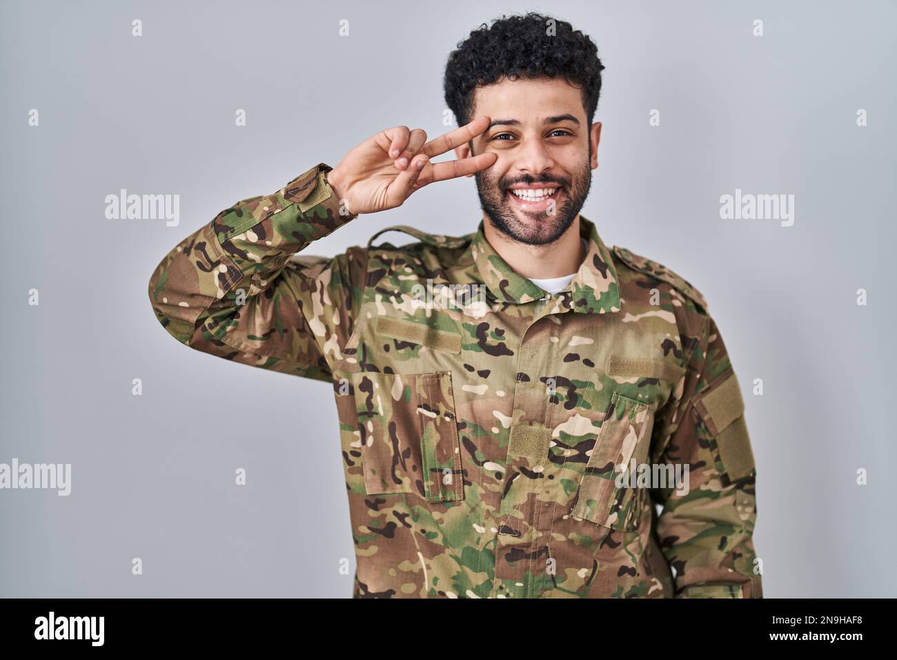 Arab man wearing camouflage army uniform doing peace symbol with ...