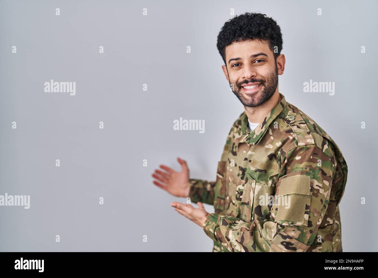 Arab man wearing camouflage army uniform inviting to enter smiling ...
