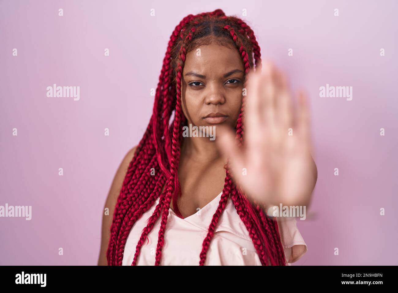 African american woman with braided hair standing over pink background ...