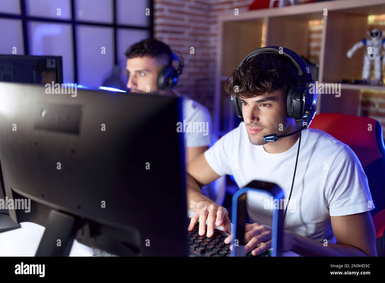 Two hispanic men streamers playing video game using computer at gaming ...