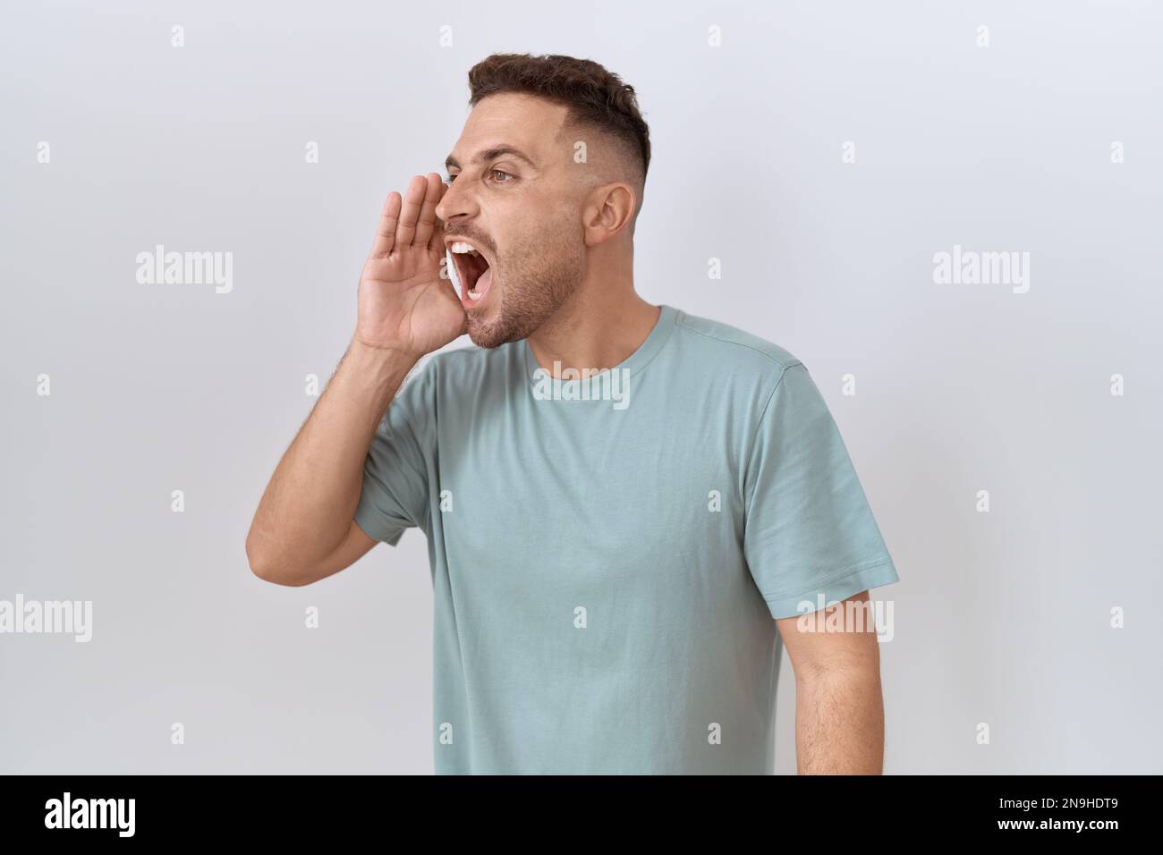 Hispanic man with beard standing over white background shouting and ...