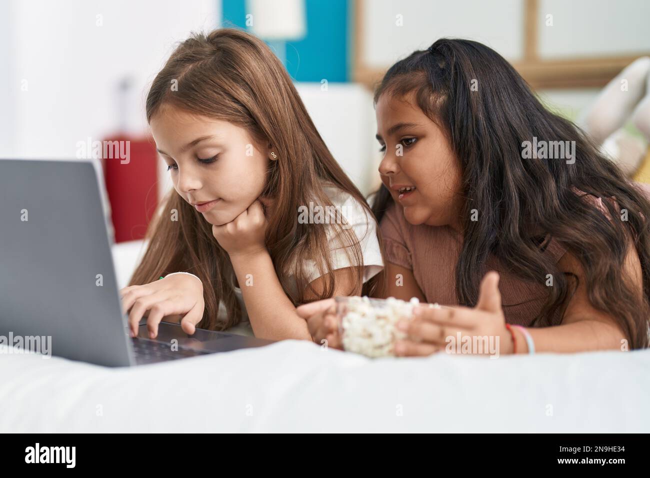 Two kids watching movie on laptop lying on bed at bedroom Stock Photo ...