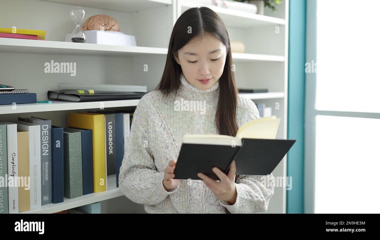 Young chinese woman student reading book studying at library university ...