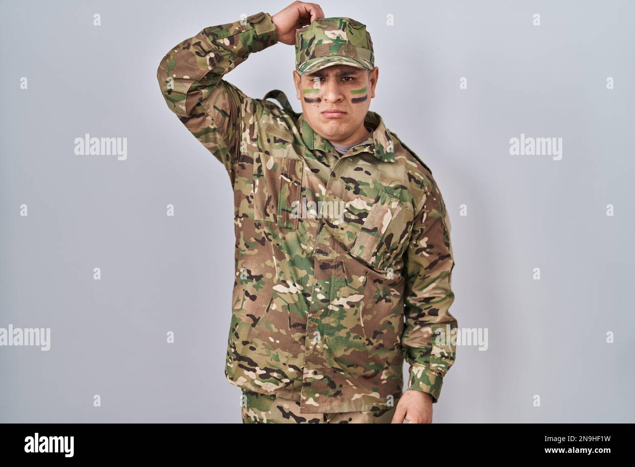 Hispanic young man wearing camouflage army uniform confuse and wonder ...