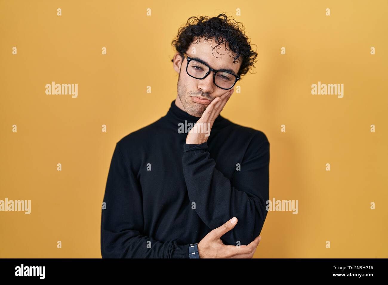 Hispanic man standing over yellow background thinking looking tired and ...
