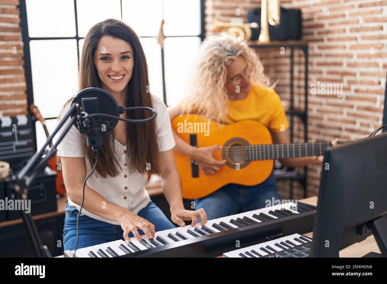 Two women musicians singing song playing classical guitar and piano at ...