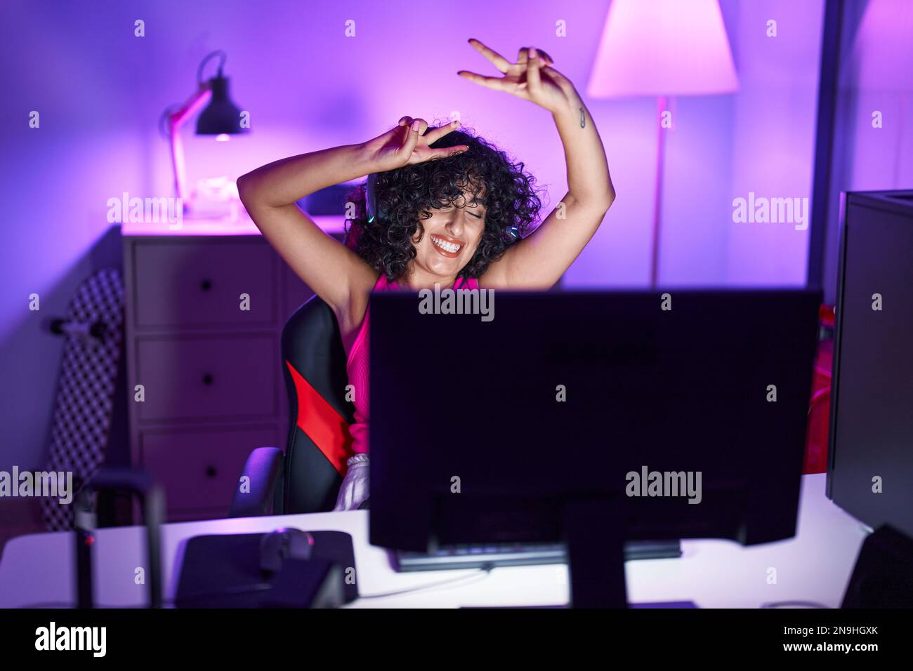 Young middle eastern woman streamer playing video game dancing at ...