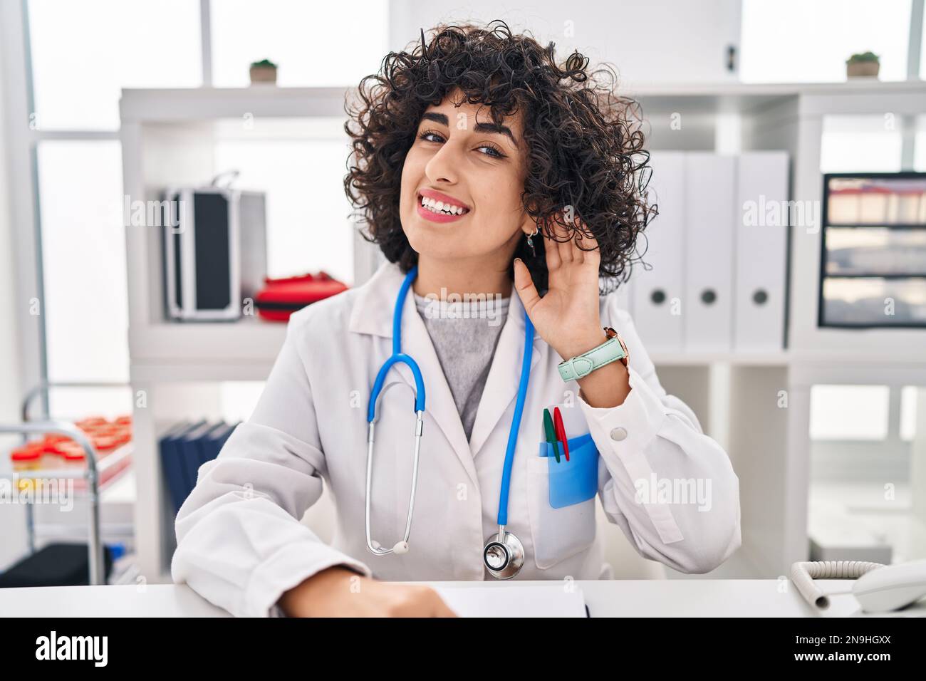 Young brunette woman with curly hair wearing doctor uniform and ...