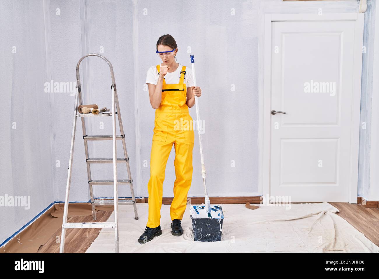 Young caucasian woman painting walls feeling unwell and coughing as ...