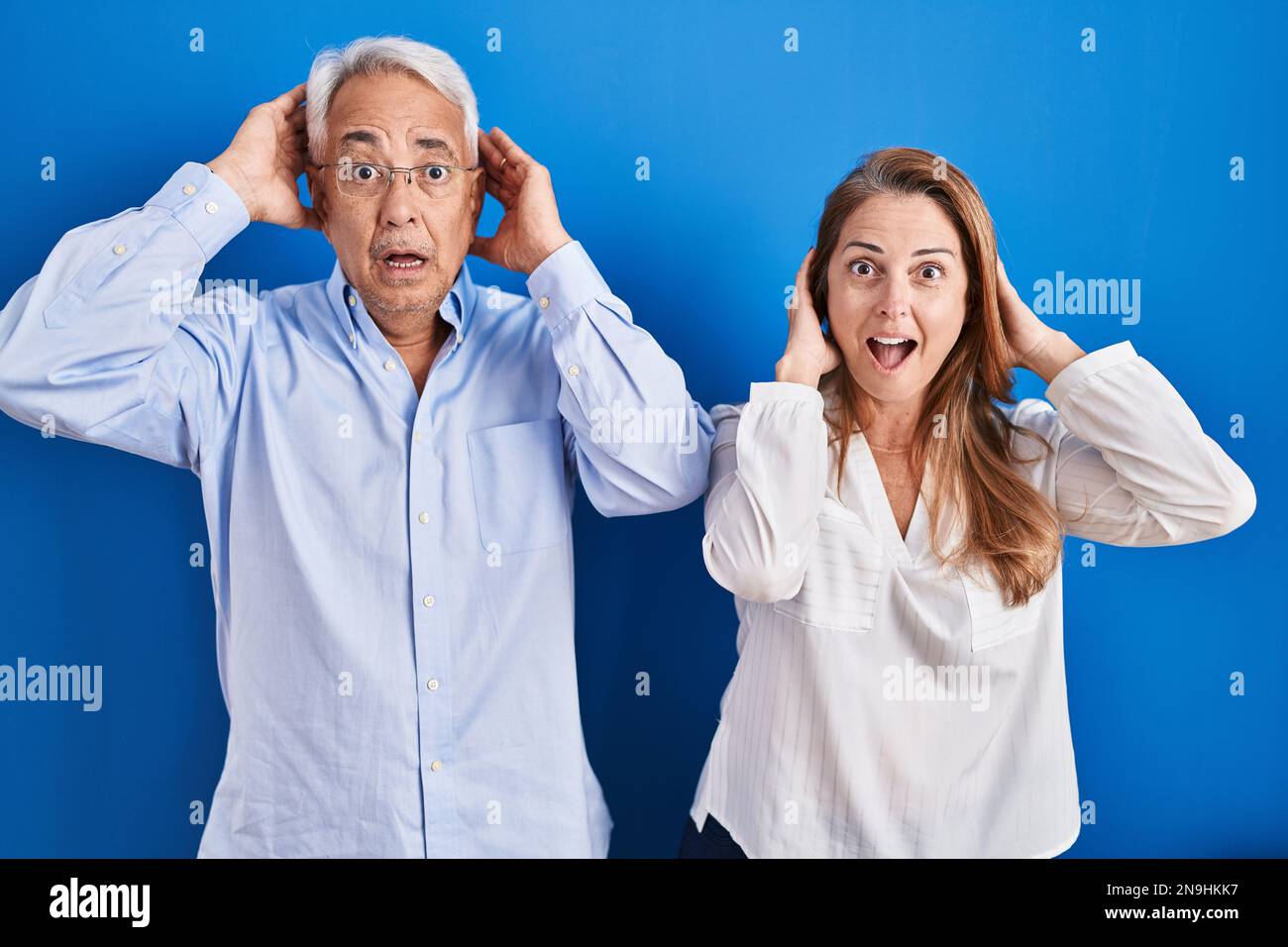 Middle age hispanic couple standing over blue background crazy and ...