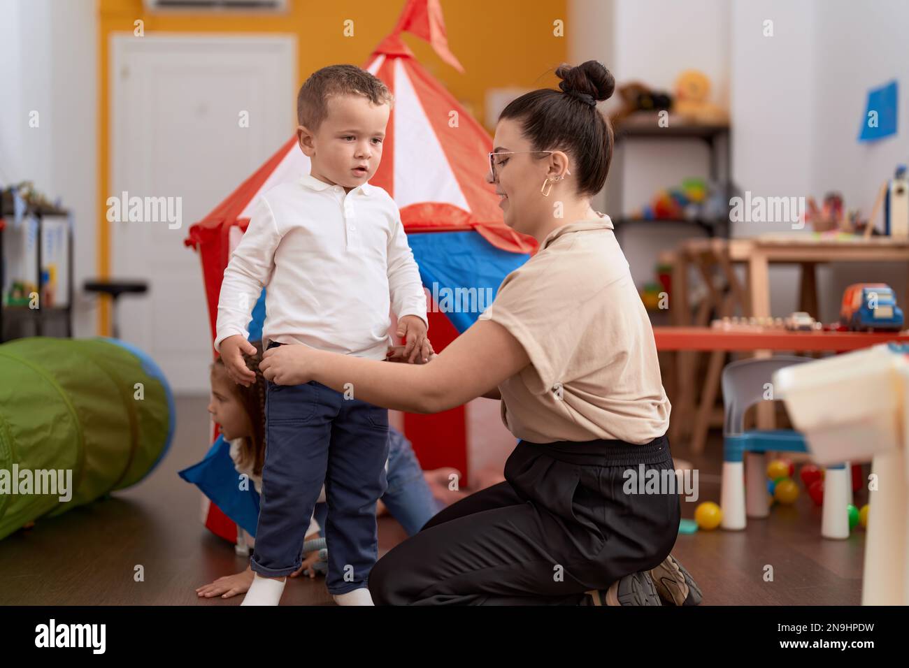 Teacher and toddler playing on circus tent sitting on floor at ...