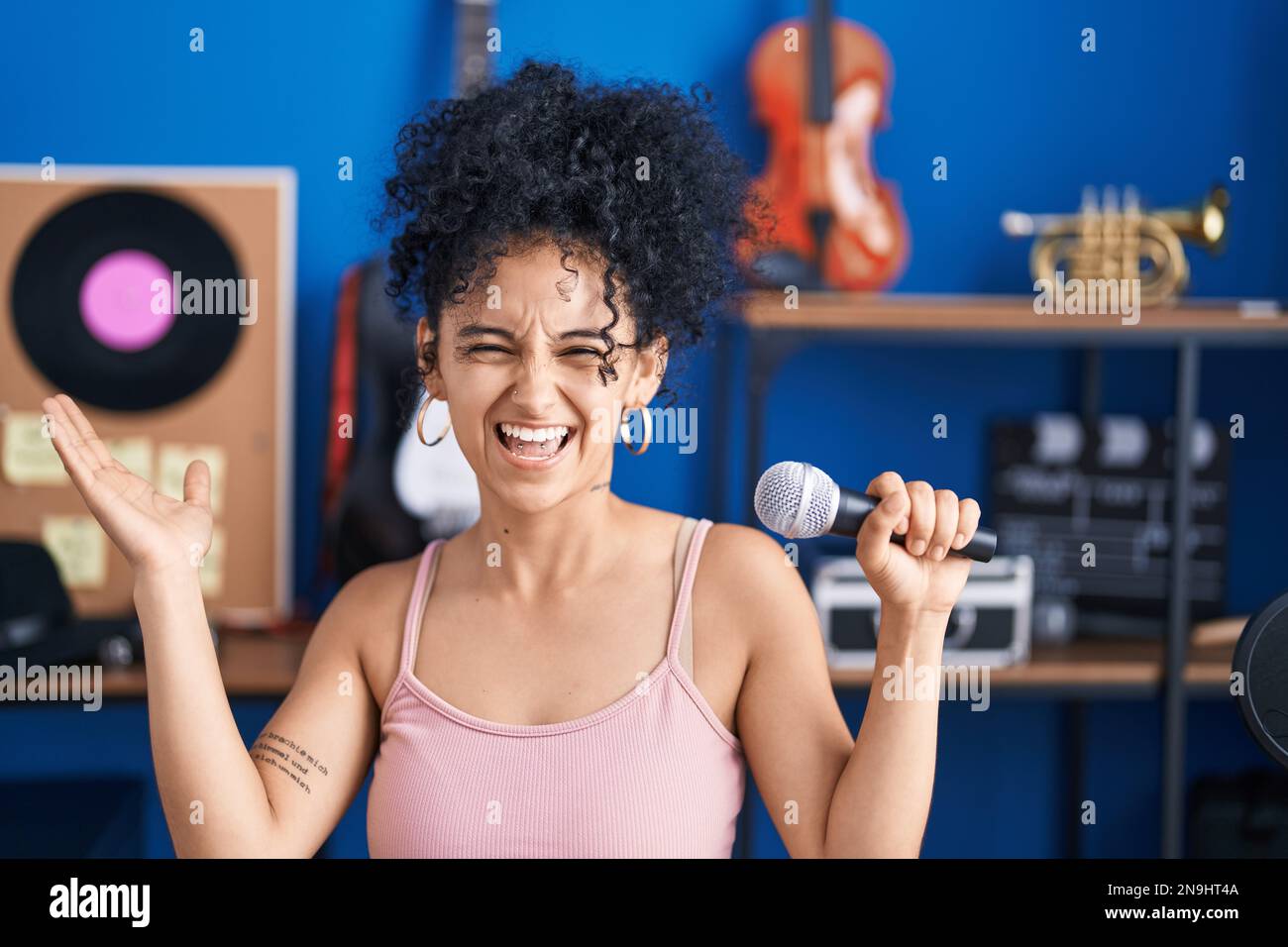 Hispanic woman with curly hair singing song using microphone at music ...