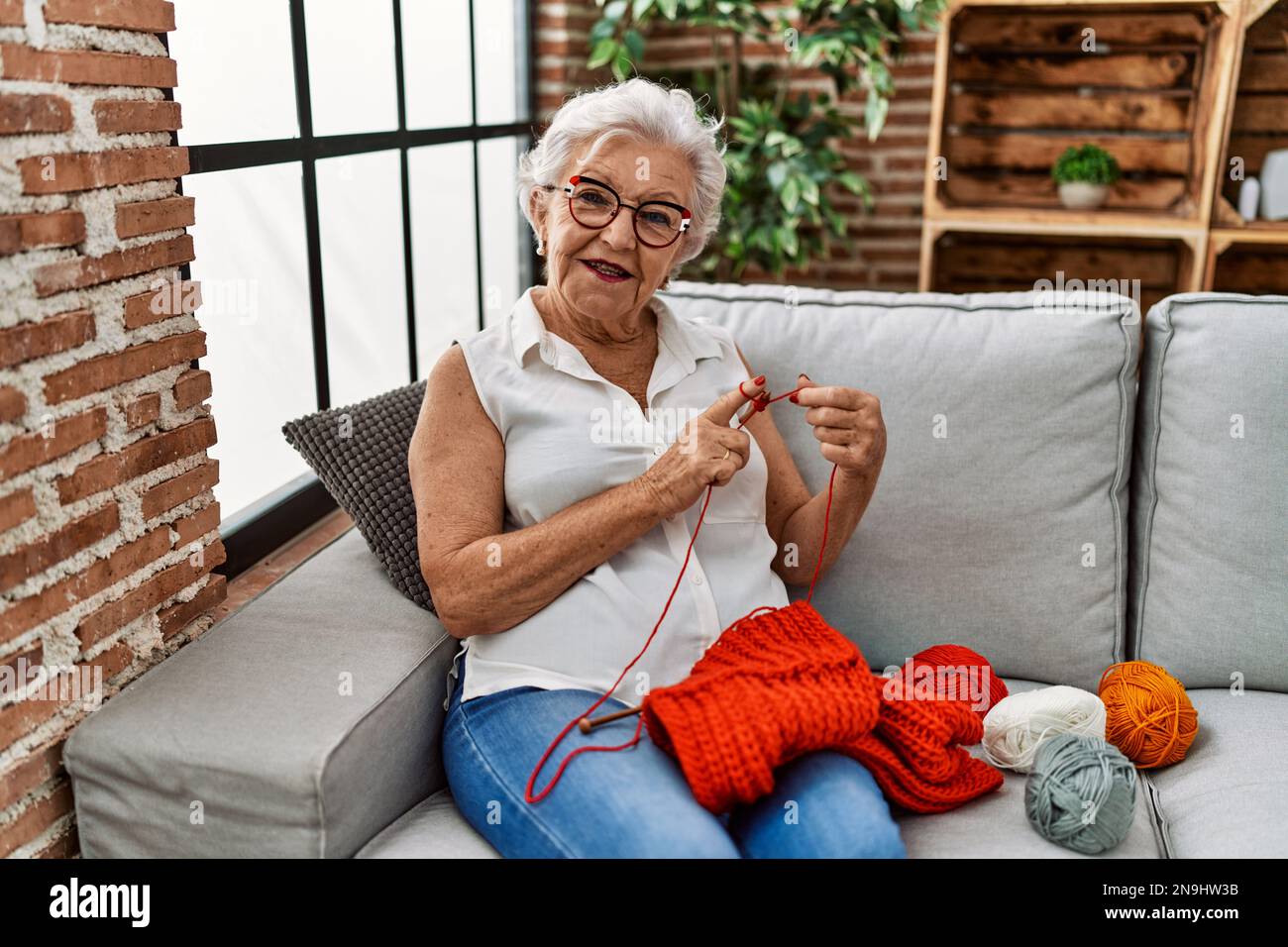 Senior grey-haired woman smiling confident sewing using lane and needle ...