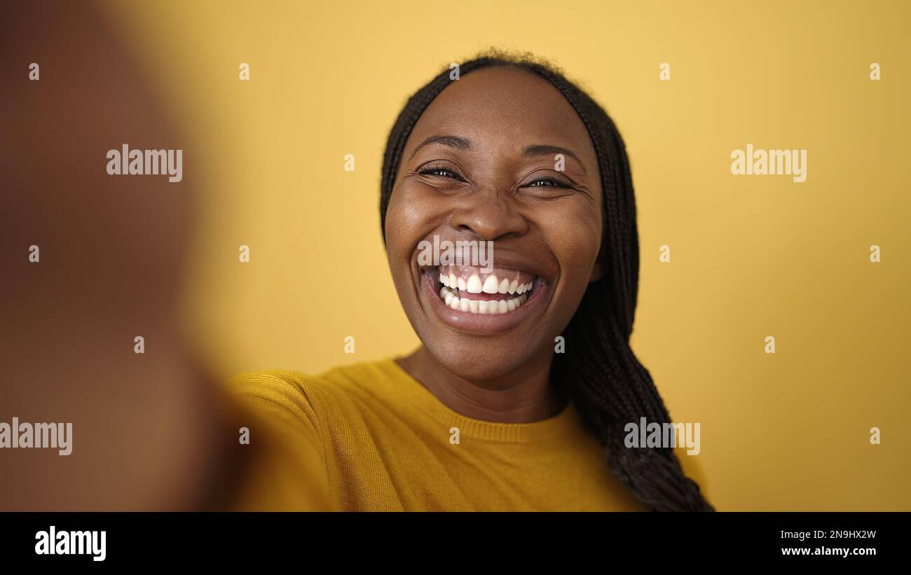 African woman taking selfie smiling over isolated yellow background ...