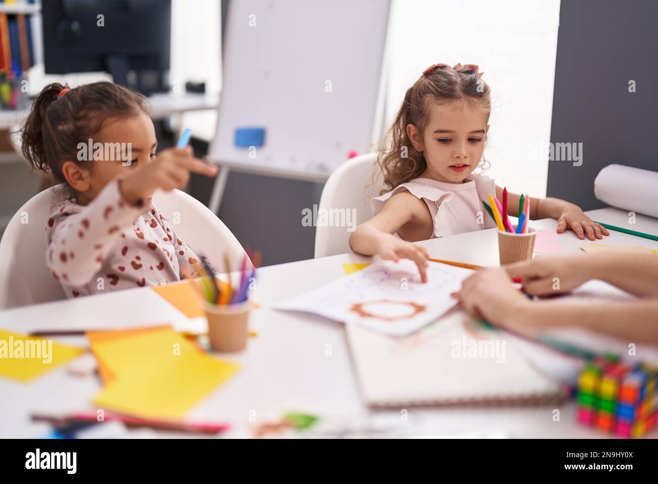 Two kids preschool students having lesson with teacher at classroom ...