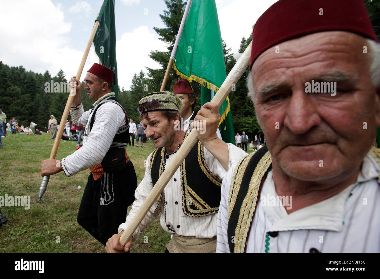 Bosnian Muslim men dressed in traditional outfits carry flags during ...