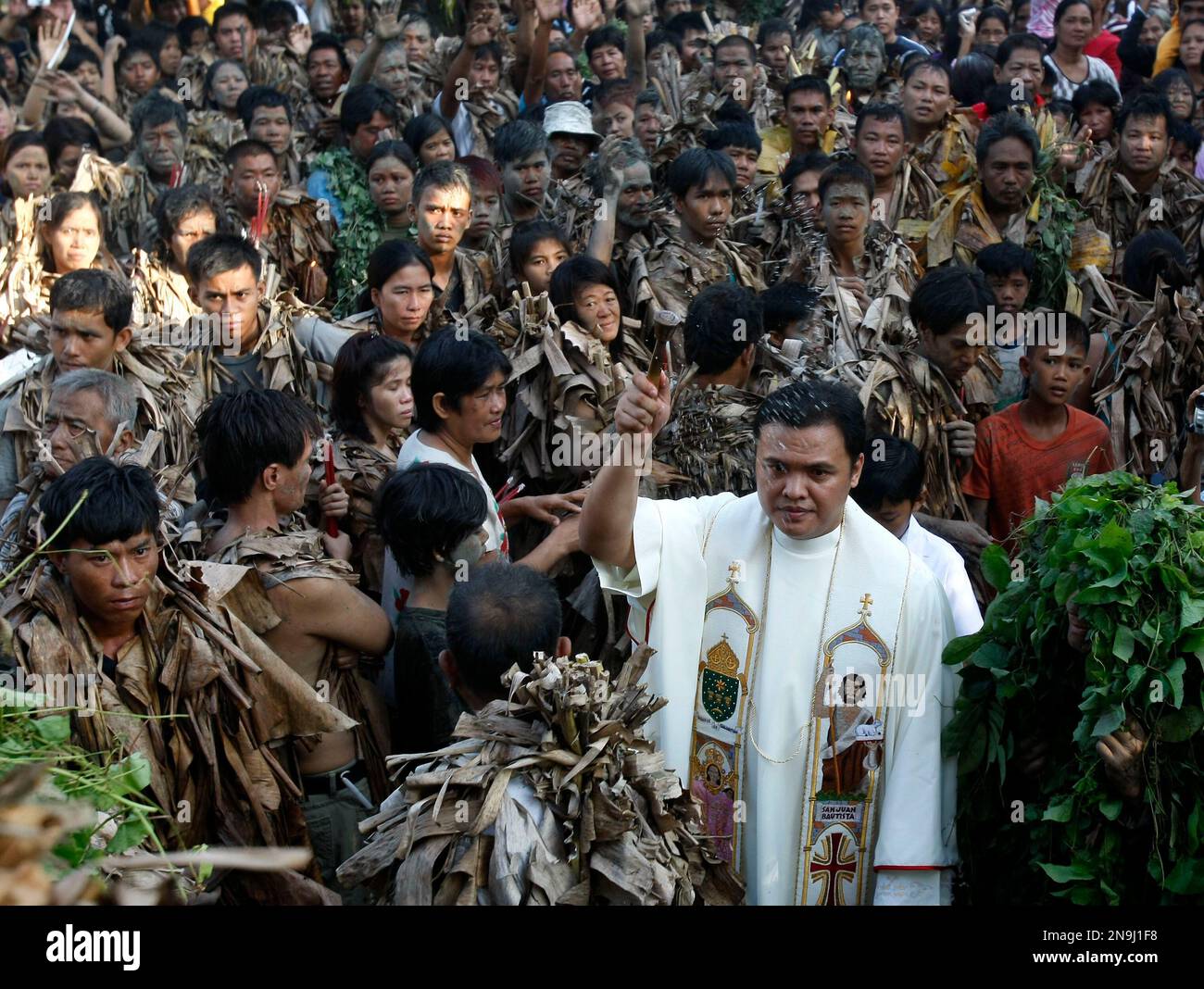 A Roman Catholic priests sprinkles holy water to devotees, who soaked ...