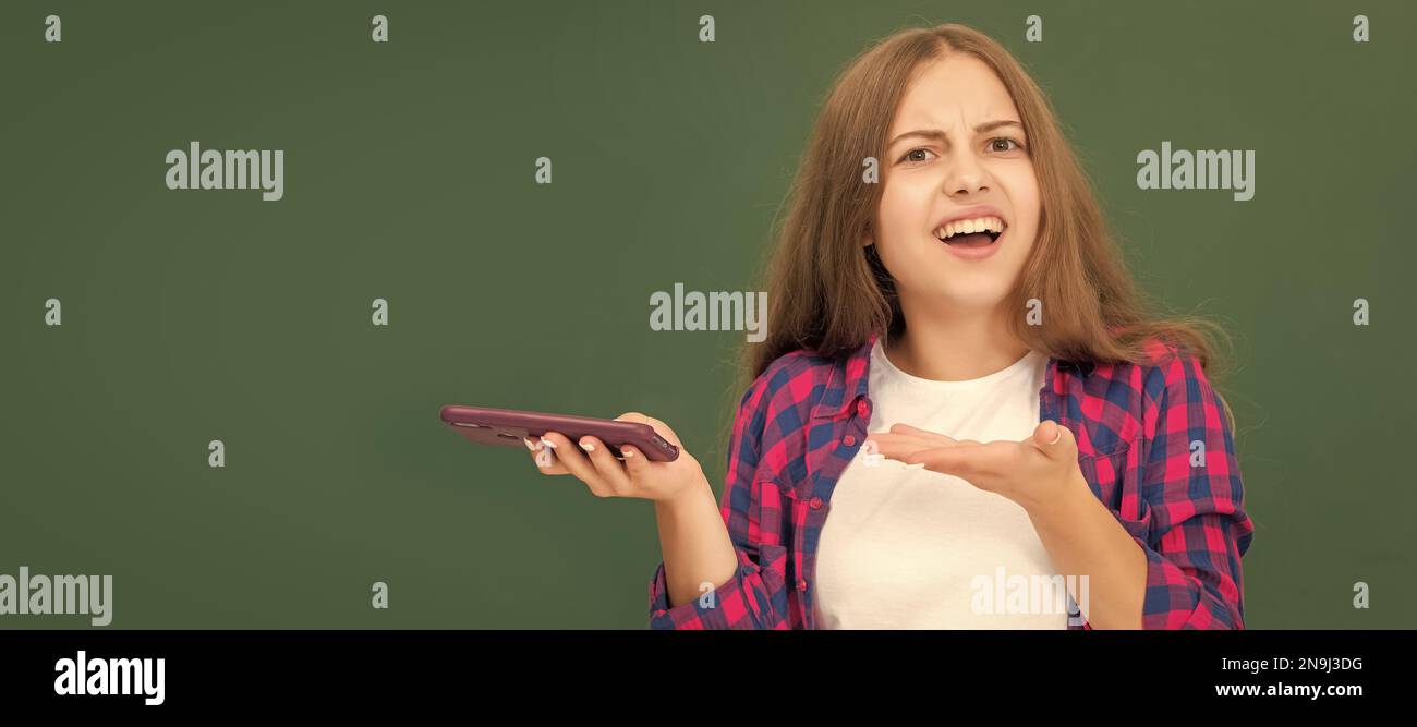 confused child at school chatting on phone on blackboard background ...