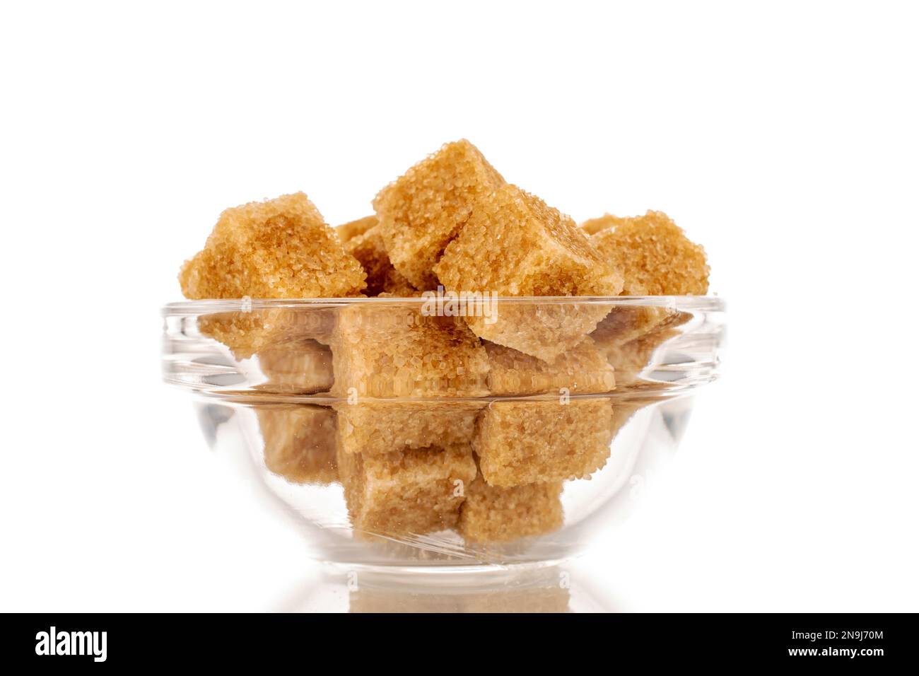 A few cubes of brown sugar in a glass dish, macro, isolated on a white ...
