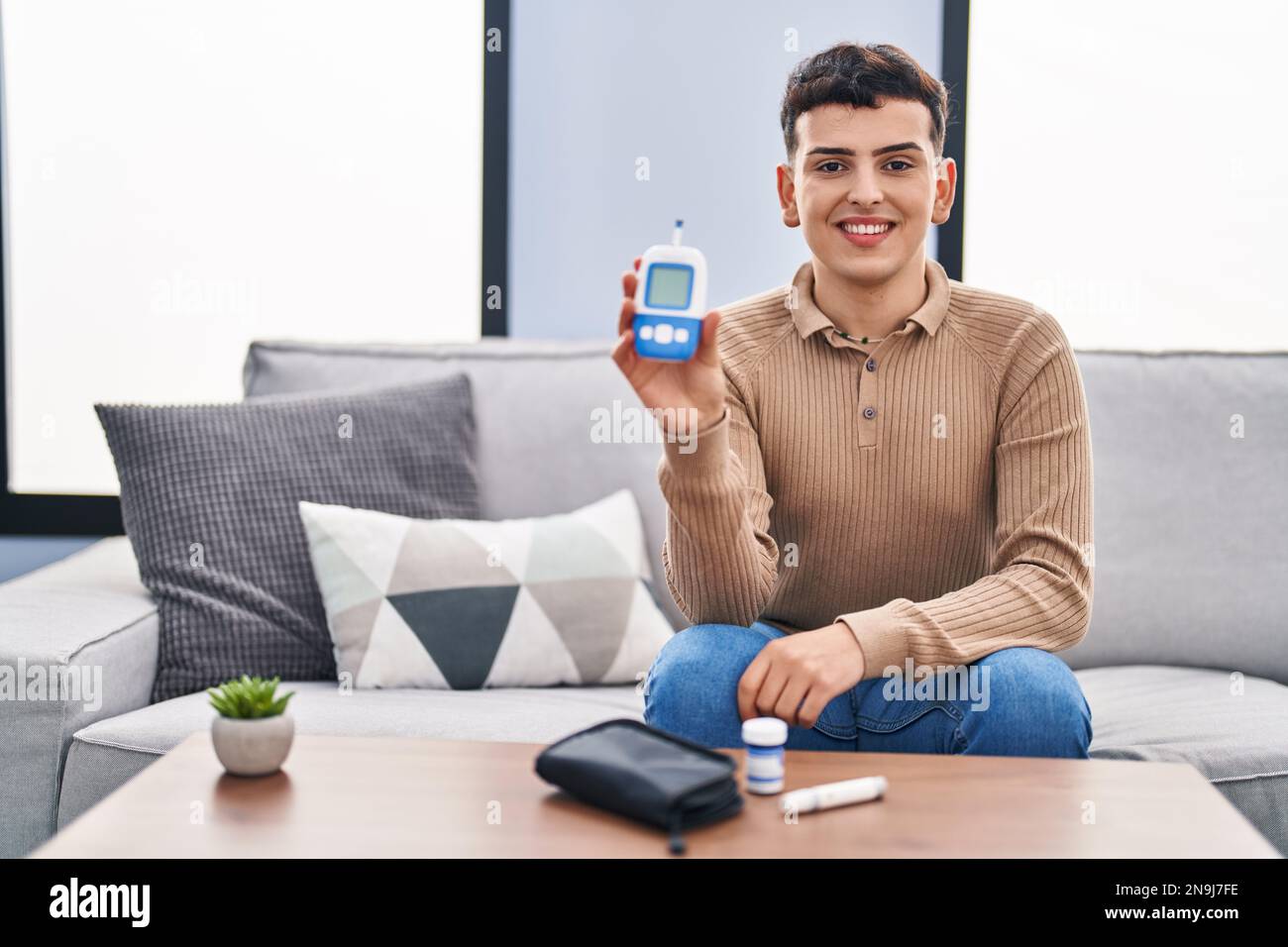 Non binary person using blood pressure monitor looking positive and ...