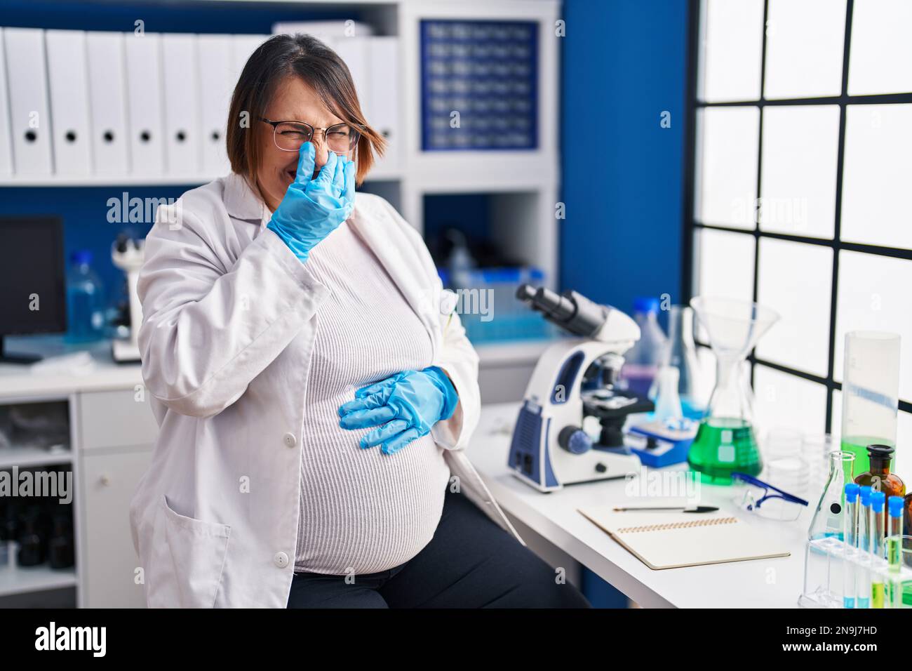 Pregnant woman working at scientist laboratory smelling something ...