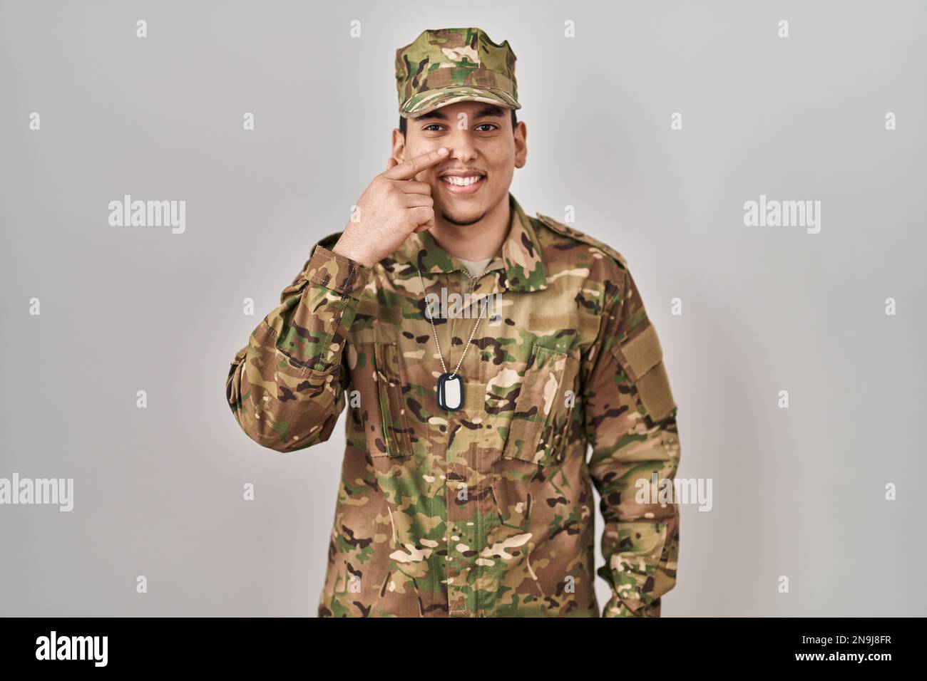 Young arab man wearing camouflage army uniform pointing with hand ...