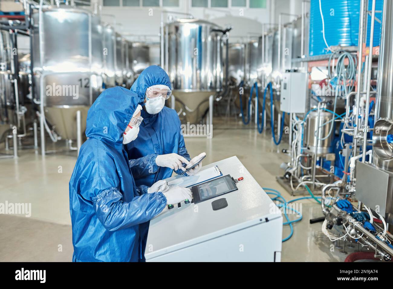 Side view portrait of two workers operating equipment at factory and ...