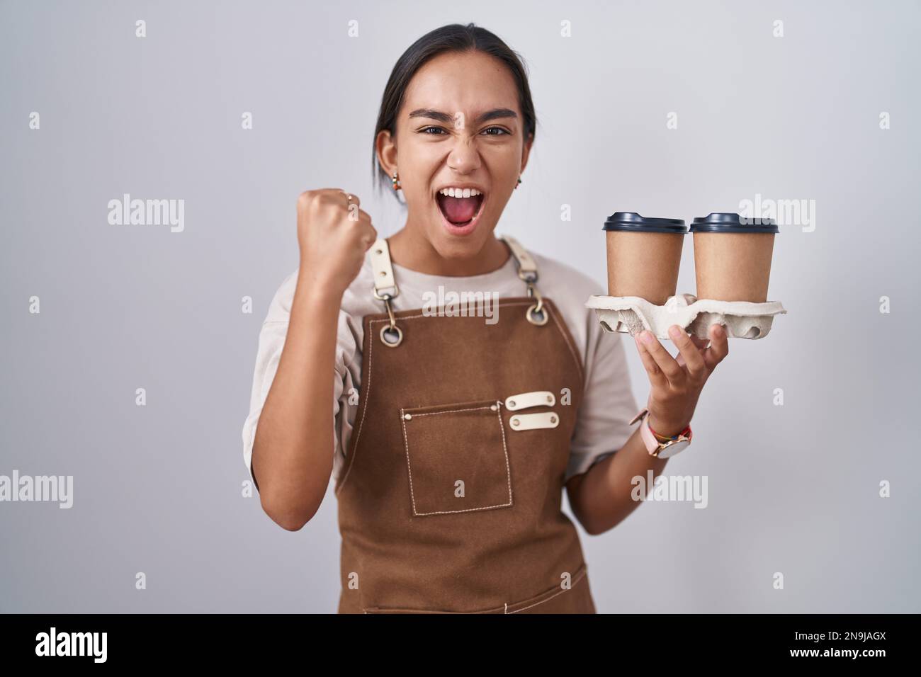 Young hispanic woman wearing professional waitress apron holding coffee ...