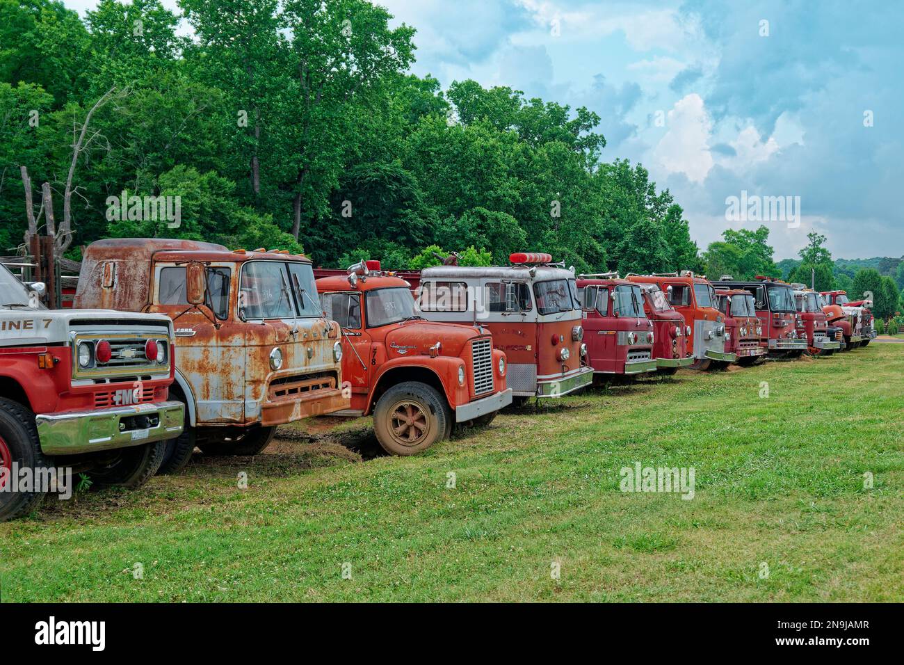 A collection of vintage fire trucks retired park together in a row in a ...