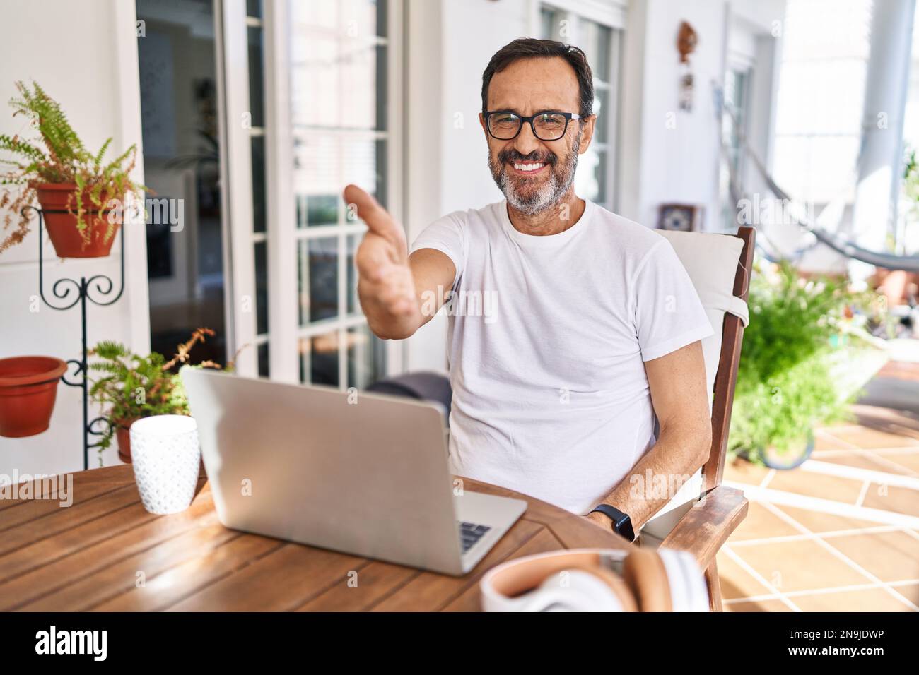 Middle age man using computer laptop at home smiling friendly offering ...